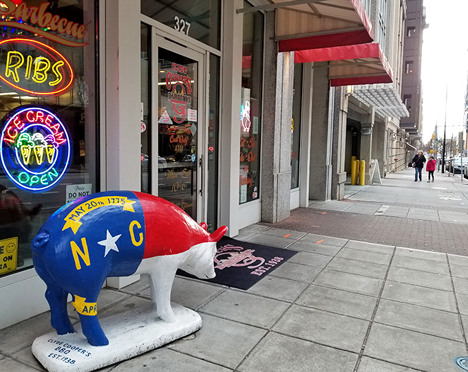 The iconic North Carolina pig statue stands guard outside Clyde Cooper's, where barbecue fame hides an unexpected fried chicken treasure.