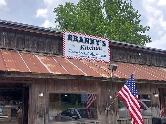 The weathered wooden exterior and iconic red-checkered sign of Granny's Kitchen stand as a promise of authentic home cooking that's kept Arkansans coming back for generations.