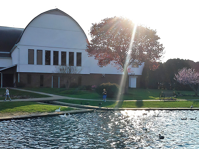 The iconic white barn structure rises majestically against the Ohio sky, with a serene pond reflecting its timeless charm. Rural dining perfection awaits.