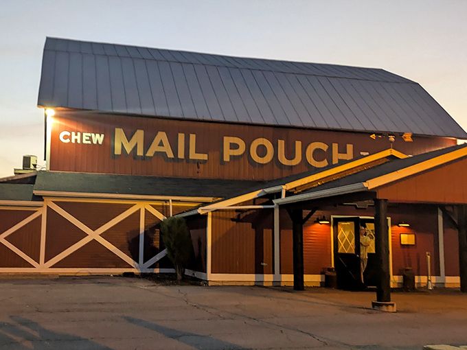 As dusk settles, the Mail Pouch sign glows with warm invitation, like a beacon calling hungry travelers home after a long day's journey.