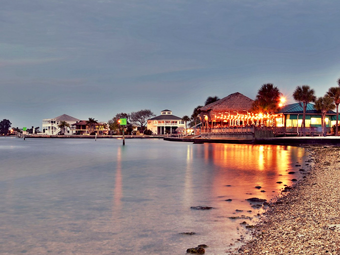 Twilight transforms Hudson's waterfront into a painting come to life, with thatched-roof restaurants casting golden reflections across the tranquil Gulf waters.