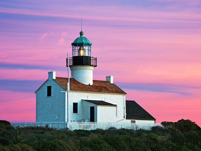 The Old Point Loma Lighthouse stands like a Victorian postcard against a cotton candy sky, its green-domed beacon a silent sentinel over San Diego's waters.