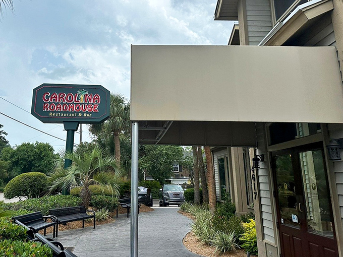 The exterior of Carolina Roadhouse, framed by tropical palm trees and its classic sign, proves that culinary treasures often hide in plain sight.