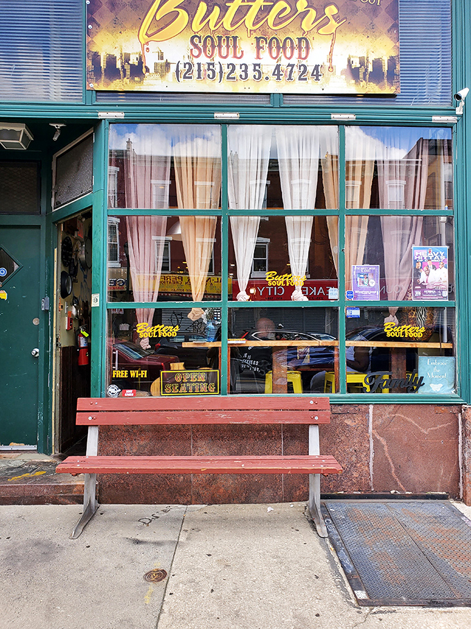 The teal storefront of Butter's Soul Food To Go stands out like a beacon of culinary promise on this Philadelphia street, complete with a welcoming bench for those inevitable wait times.