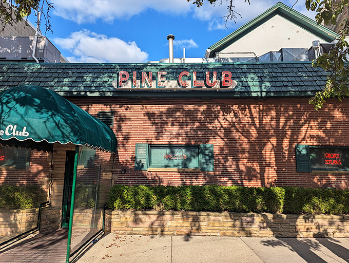 The iconic brick exterior and forest green awning of The Pine Club stands as Dayton's temple to timeless steakhouse tradition.