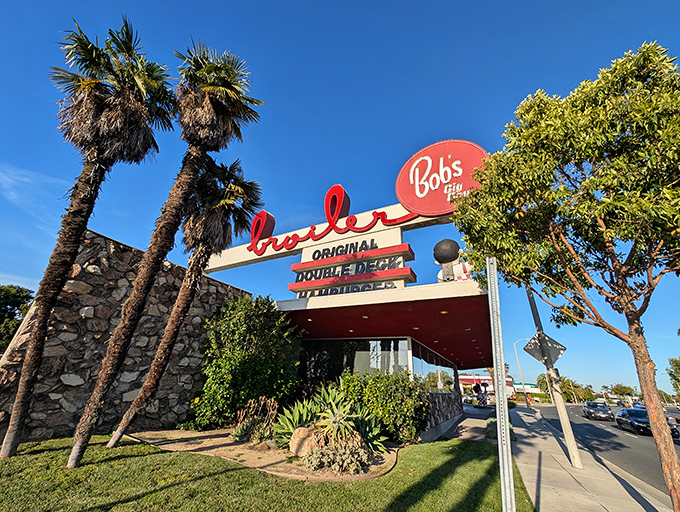Palm trees frame the legendary neon signage like nature's own exclamation points, announcing "Yes, you've arrived at burger paradise!"