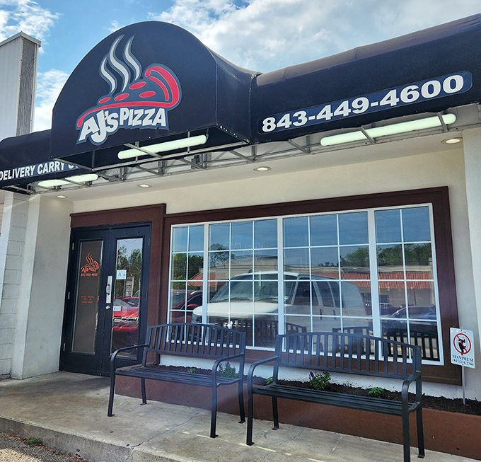The unassuming storefront of AJ's Pizza beckons with its simple black awning and welcoming benches &ndash; proof that culinary treasures often hide in plain sight.