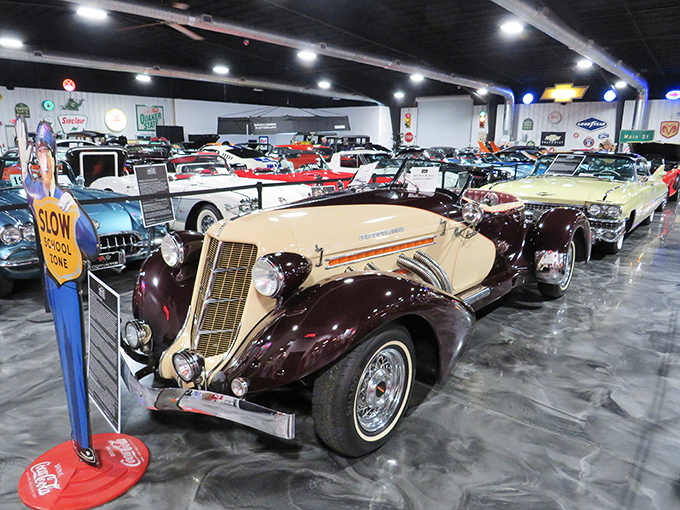A cream and burgundy Auburn Speedster steals the spotlight among rows of meticulously preserved automotive history. Chrome so shiny you might need sunglasses indoors!