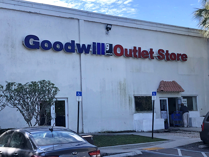 Where thrift dreams come true in blue and red. The Goodwill Outlet Store's sign stands out against the Florida sky like a beacon for bargain hunters.