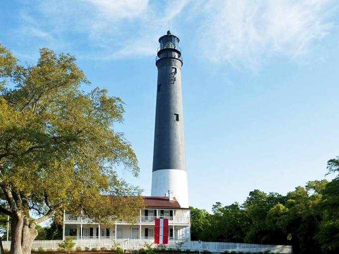 The iconic black and white tower rises majestically against Florida's blue sky, standing sentinel over Pensacola Bay since 1859.