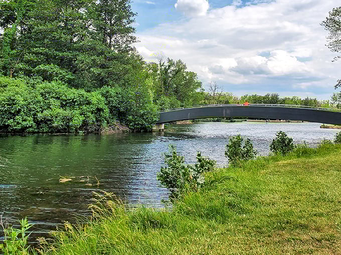 Nature's perfect postcard: A serene footbridge arches gracefully over crystal-clear waters, inviting visitors to cross into Wisconsin's woodland paradise.