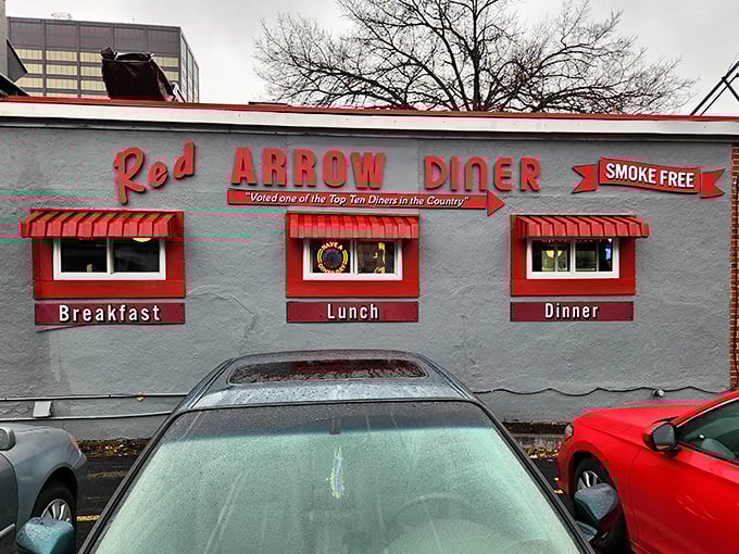The iconic Red Arrow Diner facade beckons hungry travelers with its classic red awnings and neon signage&mdash;a beacon of breakfast hope in downtown Manchester.