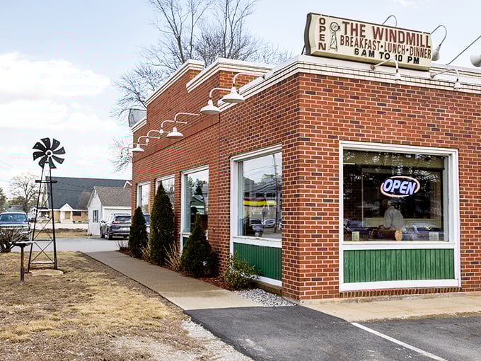 The brick exterior of The Windmill Restaurant stands as a beacon of breakfast hope, complete with its namesake windmill decoration that promises good things are spinning inside.