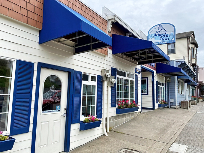 The classic coastal charm of Chowder Bowl beckons with its crisp white exterior and vibrant blue trim. Those flower boxes aren't just pretty—they're a promise of the warmth waiting inside.