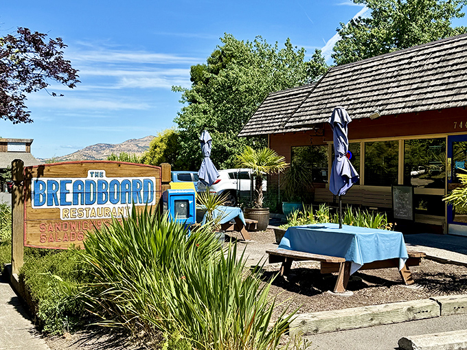 The rustic charm of The Breadboard beckons from the roadside, its blue-lettered sign promising comfort food salvation for hungry Ashland travelers.