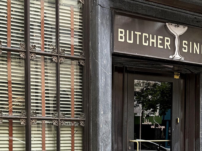 The elegant entrance to Butcher and Singer beckons like a portal to a more sophisticated era. That cocktail glass logo? A promise of good things to come.