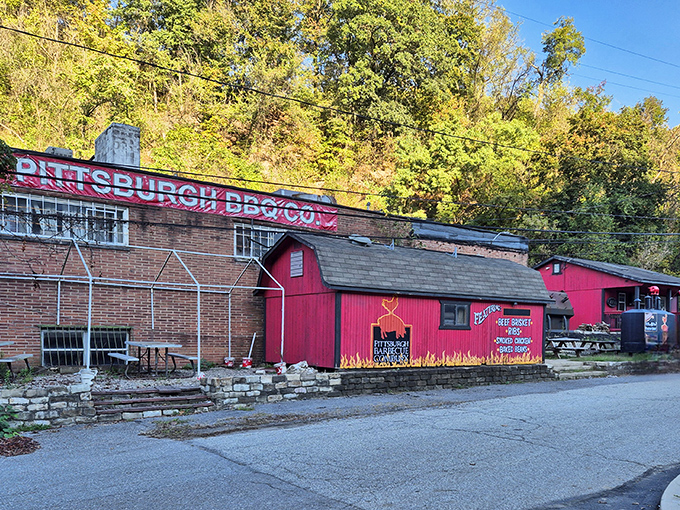 The iconic red barn structure of Pittsburgh Barbecue Company nestled against a hillside&mdash;proof that culinary treasures often hide in plain sight.