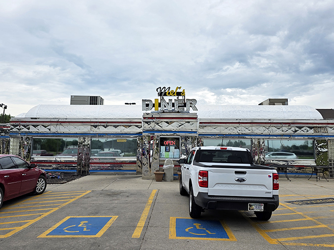 Chrome gleaming in the Nebraska sun, Mel's Diner stands like a time machine disguised as a restaurant. The classic Americana exterior promises comfort food that hugs your soul.