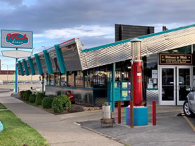 The gleaming chrome exterior of Mel's Diner shines like a beacon of breakfast hope, complete with vintage gas pump standing guard.
