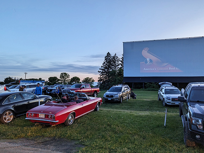 Classic cars and modern SUVs share the same patch of grass under Minnesota's twilight sky&mdash;democracy in action at the Starlite.
