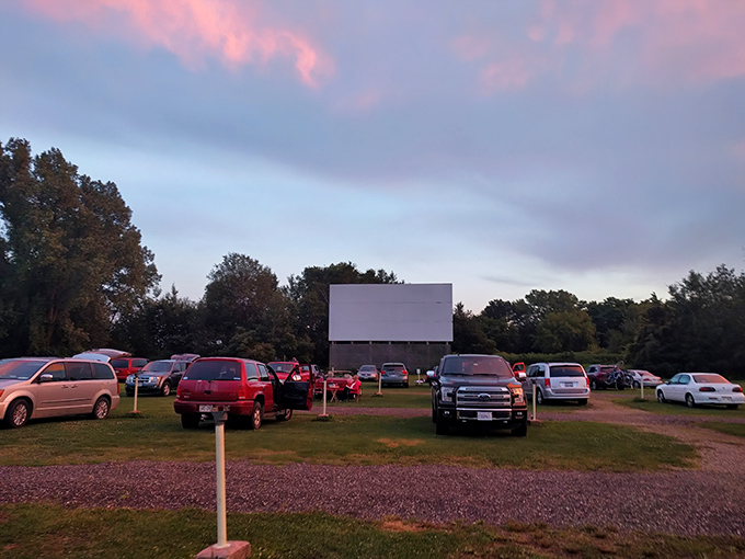 Cars lined up like eager moviegoers at their high school reunion, facing the blank canvas that will soon burst into cinematic life.