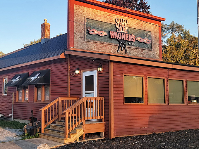 The rustic red exterior of Wagner's Ribs stands like a barbecue beacon in Porter, Indiana, promising smoky delights to all who approach.