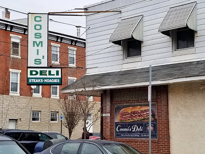 Cosmi's iconic green and white sign stands as a beacon for sandwich aficionados, promising hoagie heaven in South Philly's bustling streets.