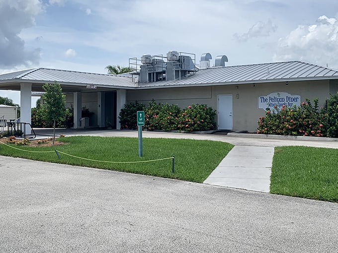 The unassuming exterior of Pelican Diner stands like a culinary speakeasy – hiding extraordinary flavors behind its modest façade and flowering bushes.