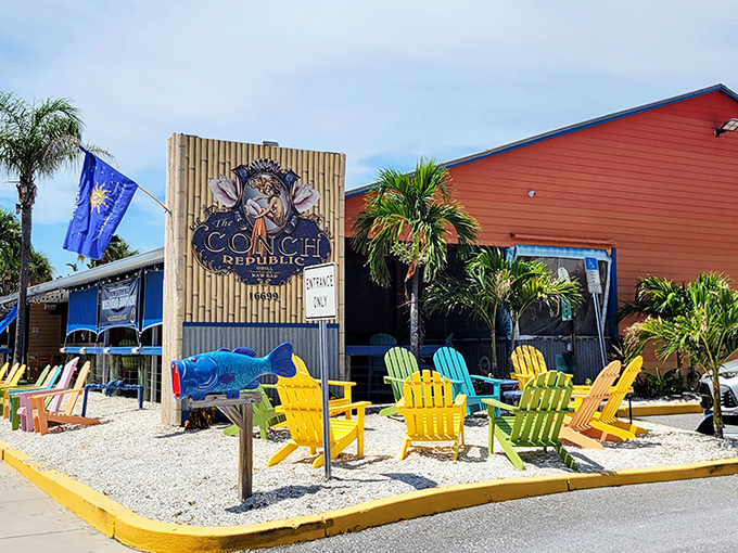 The rainbow-hued exterior of Conch Republic Grill North stands out like a tropical oasis against Florida's blue sky, palm trees swaying in welcome.