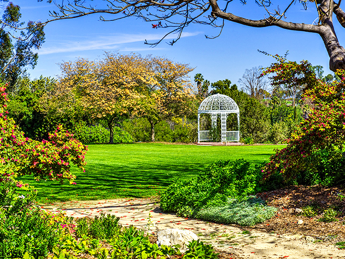 The iconic white gazebo stands like a wedding cake centerpiece amid vibrant greenery, beckoning visitors to pause and soak in the garden's splendor.
