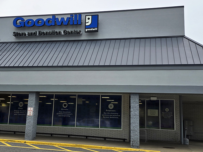 The iconic blue Goodwill sign beckons like a lighthouse for bargain hunters navigating the sea of retail mediocrity.