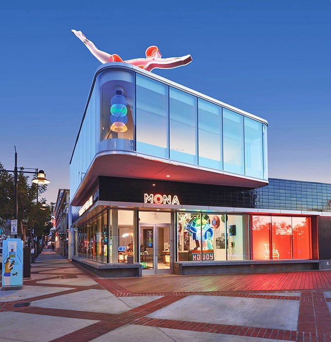 The Museum of Neon Art's striking glass facade transforms into a luminous jewel box at dusk, with its iconic red diver eternally poised mid-plunge above Brand Boulevard.