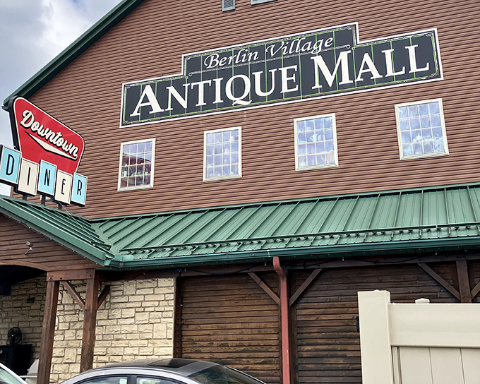 The barn-like exterior of Berlin Village Antique Mall promises treasures within, while that Downtown Diner sign whispers sweet nothings about post-antiquing sustenance.
