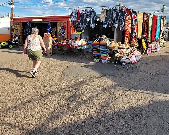 Colorful textiles and handcrafted goods beckon shoppers into this vibrant stall. The desert sun creates long shadows as treasure hunters begin their quest.
