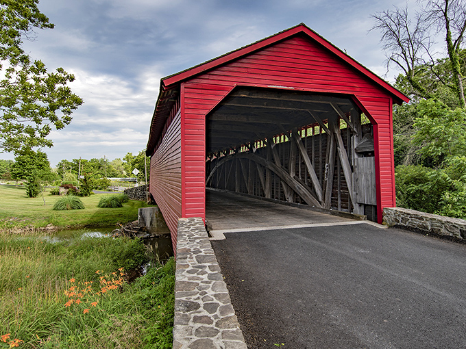 The Utica Covered Bridge stands like a crimson sentinel against Maryland's countryside, its classic design a testament to bygone craftsmanship.