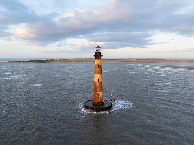 The Morris Island Lighthouse stands proudly in the Atlantic, a striped sentinel that's seen more history than a Ken Burns documentary.