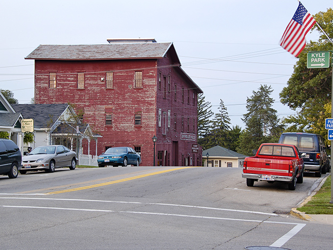 A weathered red mill building stands as Tipp City's silent historian, with Kyle Park signage visible nearby &ndash; architectural poetry from another era.