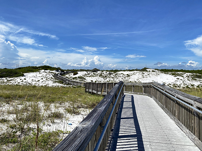 Wooden boardwalks wind through pristine dunes like nature's welcome mat, inviting you to discover what lies beyond that perfect blue horizon.