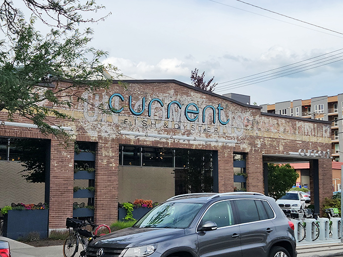 The weathered brick exterior of Current Fish & Oyster stands like a culinary time machine&mdash;industrial chic meets seafood sanctuary in downtown Salt Lake City.
