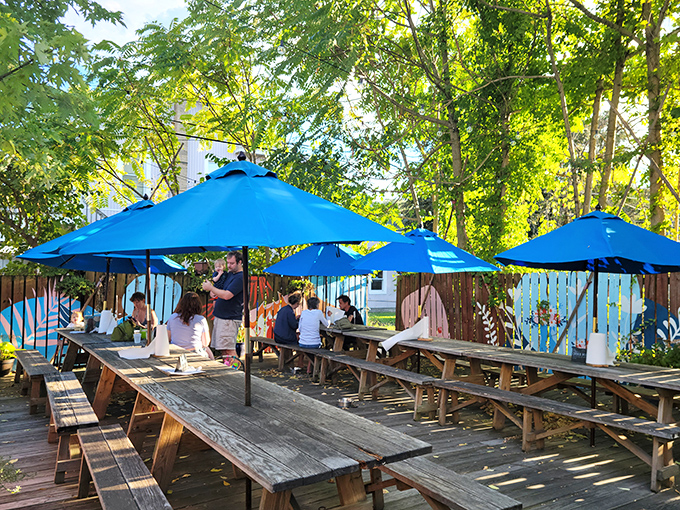 Summer paradise found! Blue Pit's dog-friendly patio offers shaded wooden picnic tables under bright blue umbrellas—the perfect setting for barbecue bliss on a sunny Baltimore afternoon