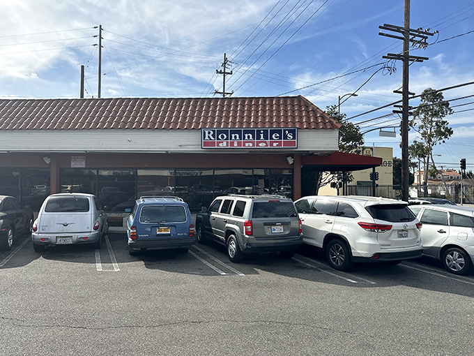 The iconic blue and red sign of Ronnie's Diner stands proudly against the California sky, promising breakfast salvation beneath that distinctive terra cotta roof.