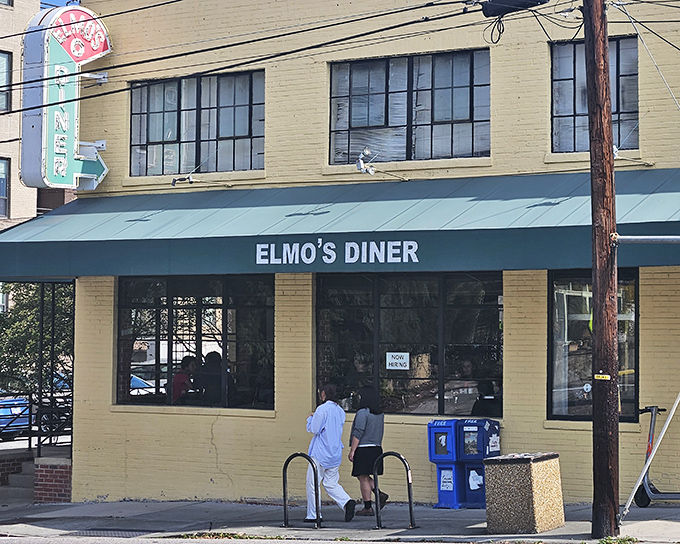 The iconic neon sign beckons hungry travelers like a lighthouse guiding ships to breakfast harbor. Elmo's yellow-brick exterior promises comfort inside.