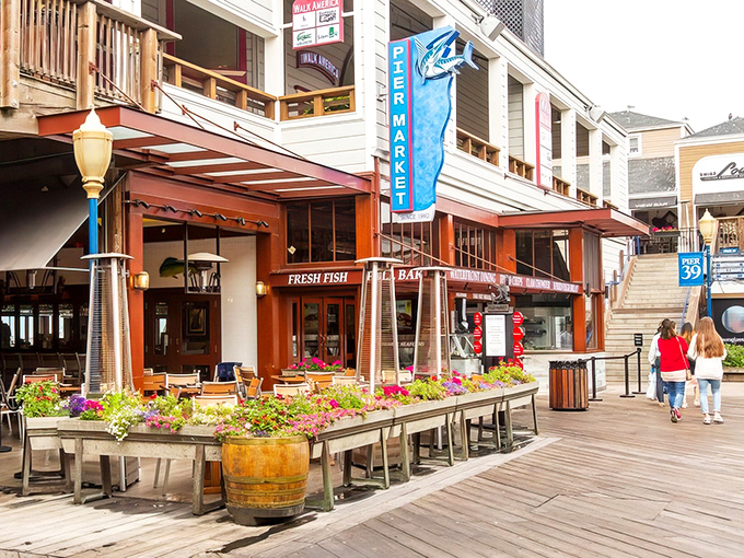The welcoming facade of Pier Market beckons seafood lovers with its bright blue signage and flower-adorned outdoor seating area.