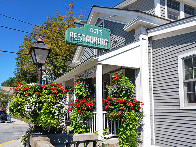 The iconic green sign beckons like an old friend, while hanging flower baskets create a Vermont welcome that's prettier than a postcard.