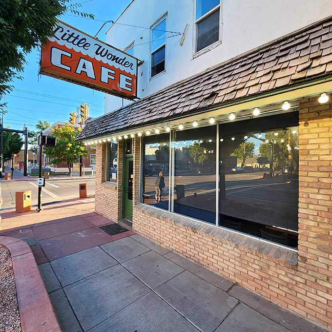 The iconic orange sign beckons like a lighthouse for hungry travelers. Little Wonder Cafe's brick exterior promises comfort food treasures within.