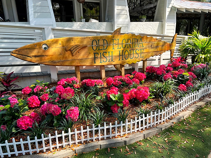 The iconic fish-shaped sign welcomes you like an old friend. Lush tropical plants frame this wooden masterpiece, promising seafood adventures ahead.
