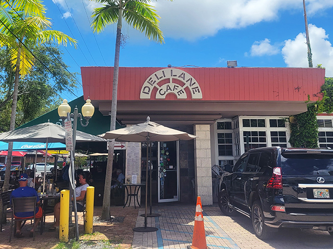 Deli Lane's iconic red awning stands as a beacon for breakfast lovers, promising poached egg perfection and patio pleasures under Florida's brilliant blue skies.
