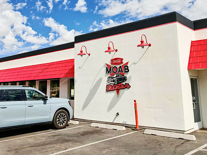 The classic red and white exterior of Moab Diner stands out against Utah's blue sky like a beacon for hungry travelers seeking comfort food salvation.