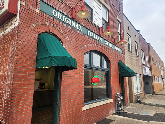 The iconic brick façade of Police Station Pizza, with its classic green awnings, stands as a beacon of rectangular pizza perfection on Ambridge's Merchant Street.