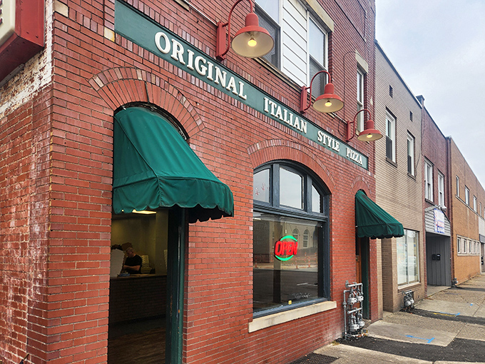 The iconic brick facade of Police Station Pizza with its distinctive green awnings stands as a beacon for pizza pilgrims. No fancy frills, just pizza perfection waiting inside.